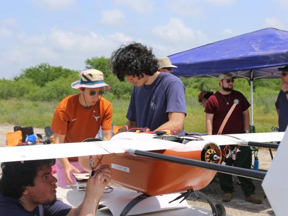 Three researchers work on orange drone.